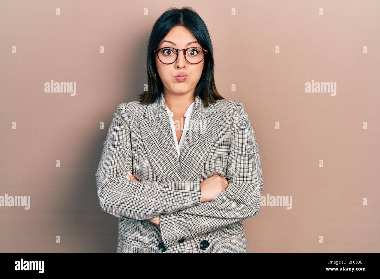 Young hispanic woman with arms crossed gesture puffing cheeks with ...