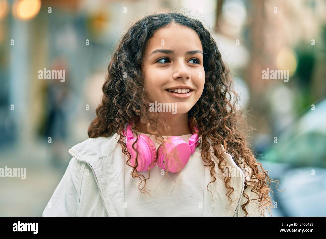 Hispanic child girl smiling happy using headphones at the city Stock ...