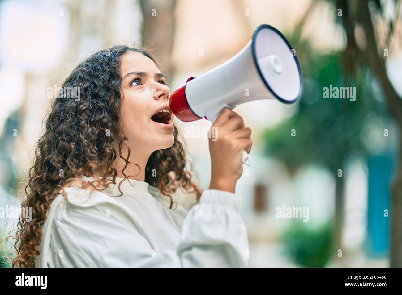 Hispanic child girl shouting angry using megaphone at the city Stock ...