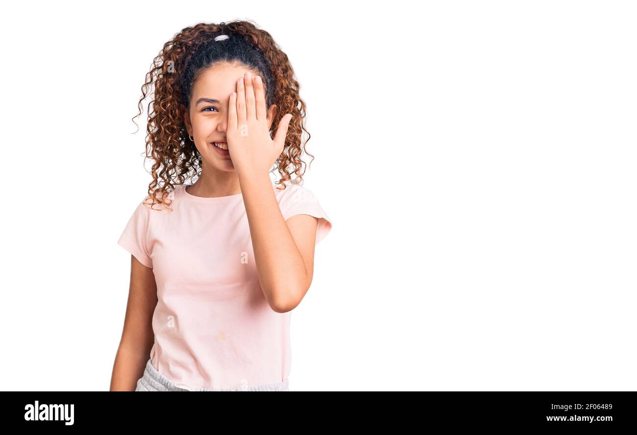 Beautiful kid girl with curly hair wearing casual clothes covering one ...