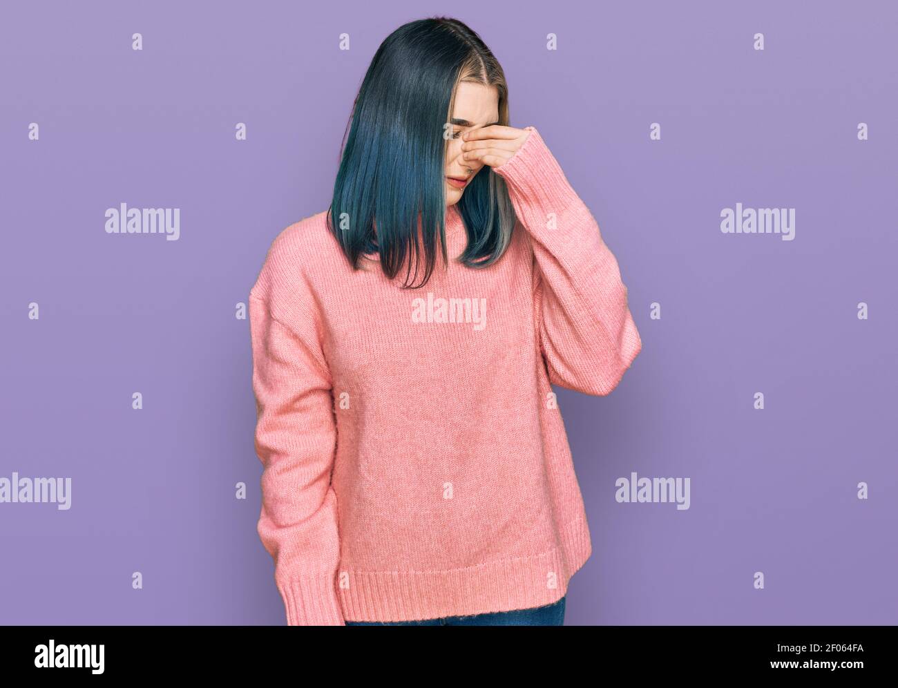 Young modern girl wearing pink wool winter sweater tired rubbing nose ...
