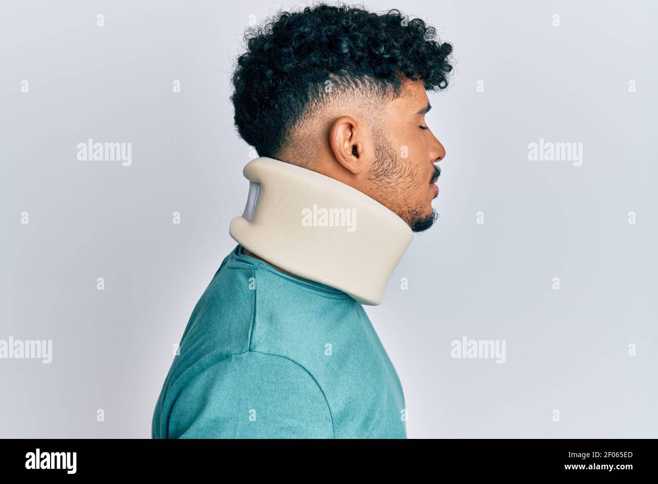 Young arab handsome man wearing cervical neck collar looking to side ...