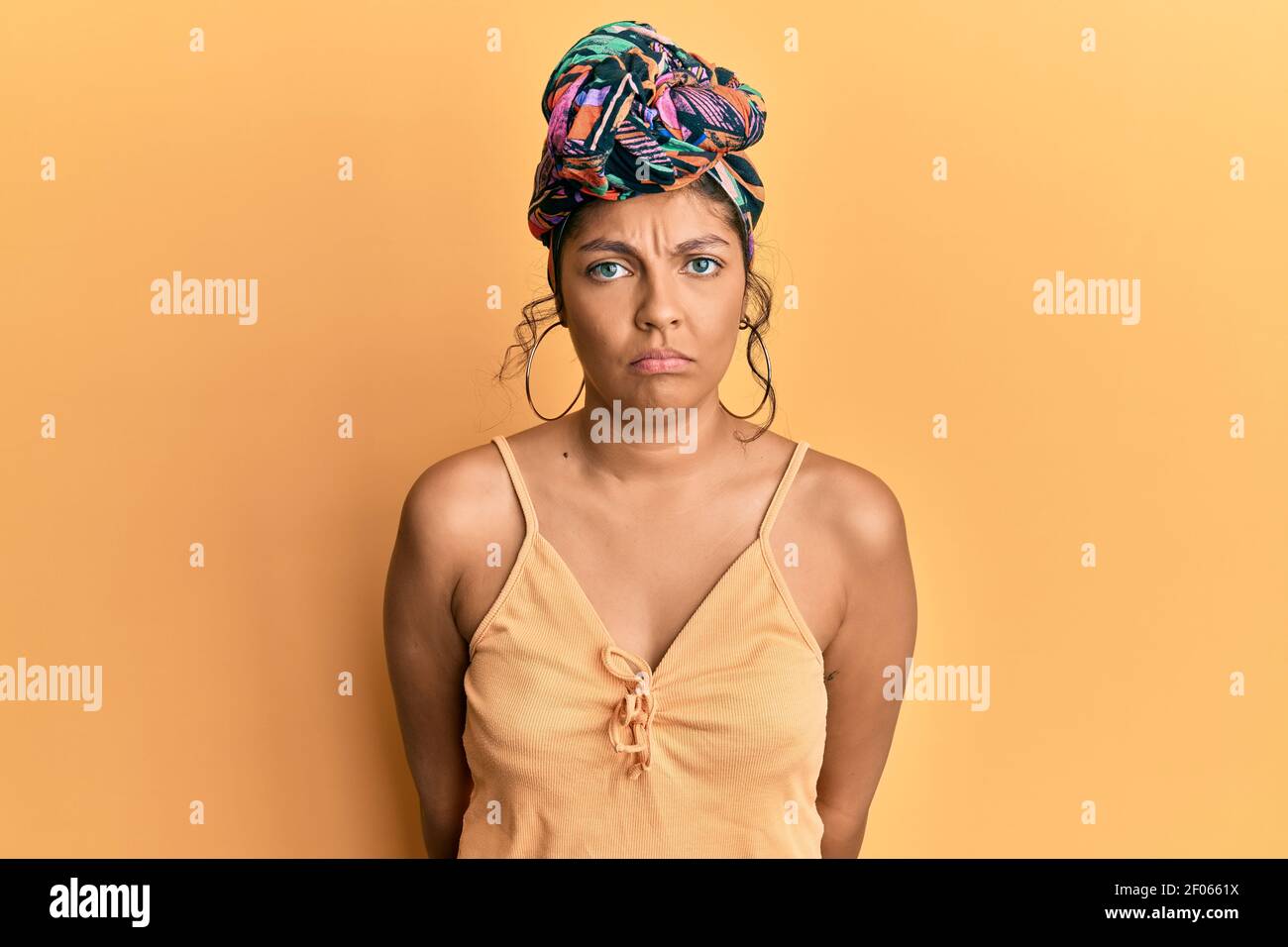 Young hispanic girl wearing hair turban over yellow background ...
