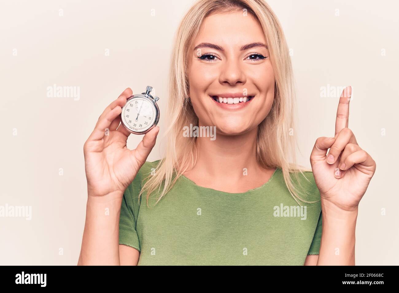 Young beautiful blonde woman doing countdown using stopwatch over white ...