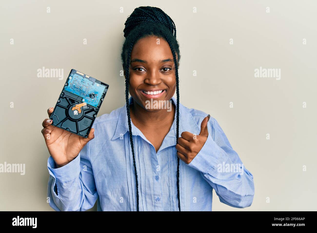 African american woman with braided hair holding hard disk smiling ...