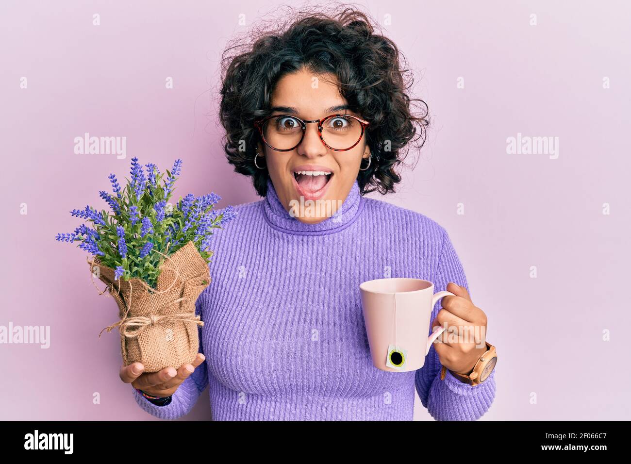 Young hispanic woman with curly hair drinking a cup of infused lavender ...