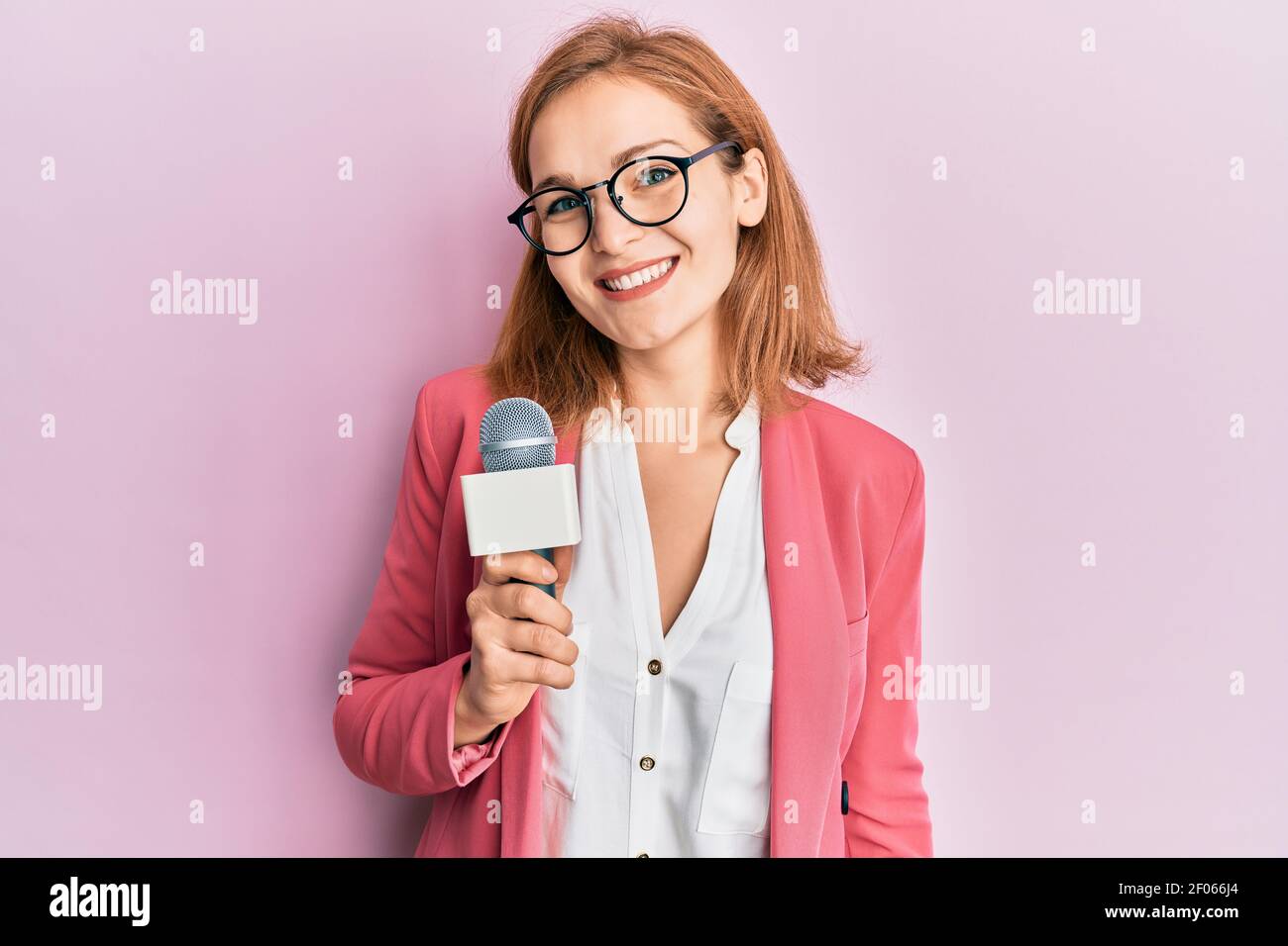 Young caucasian woman holding reporter microphone looking positive and ...