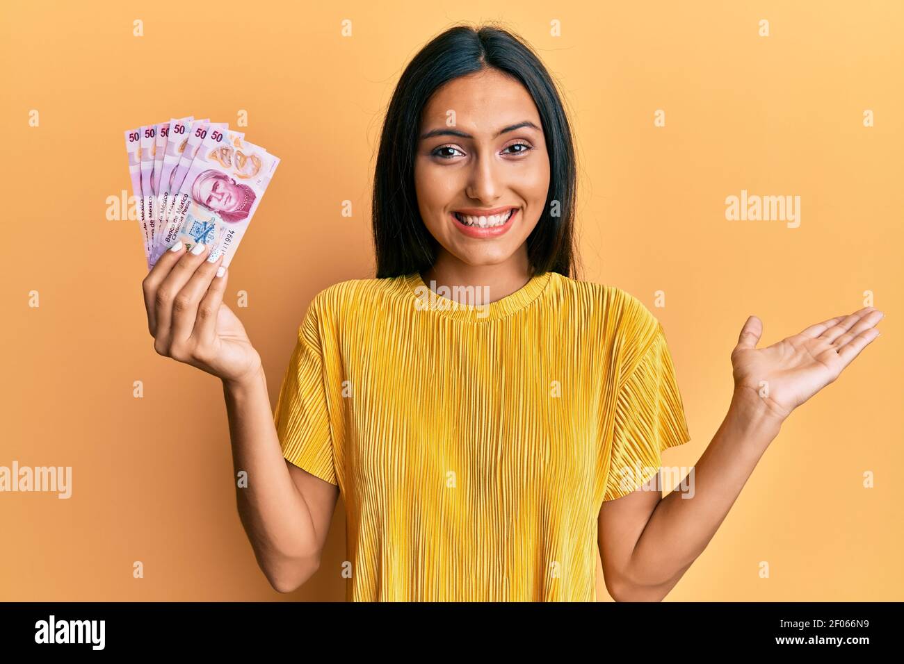 Young brunette woman holding 50 mexican pesos banknotes celebrating ...