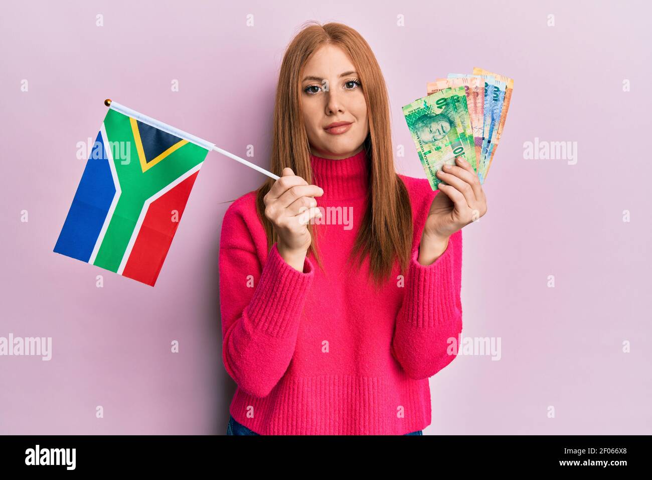 Young irish woman holding south africa flag and rand banknotes relaxed ...