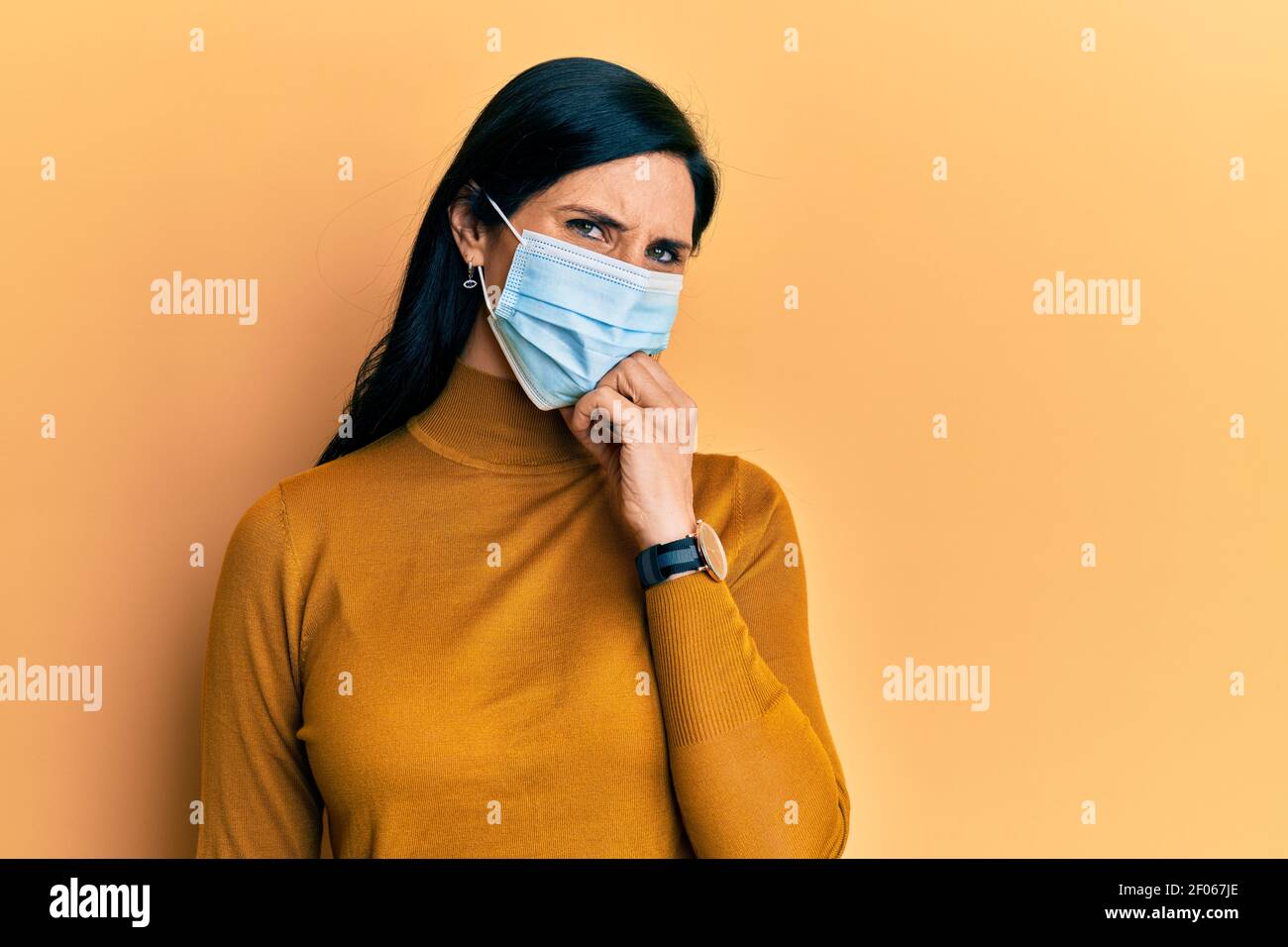 Young caucasian woman wearing medical mask thinking concentrated about ...