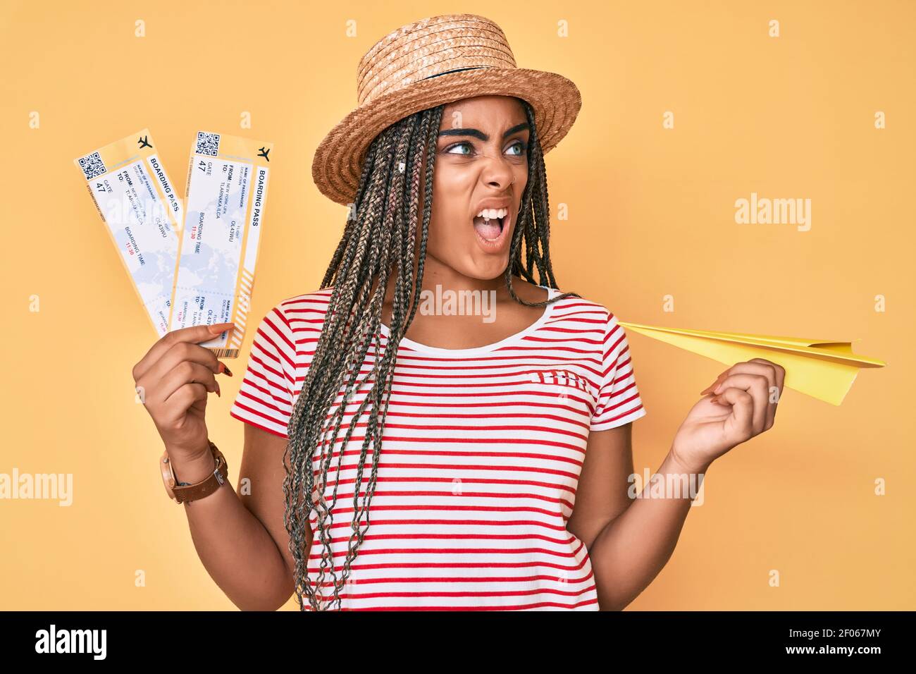 Young african american woman with braids holding paper airplane and ...