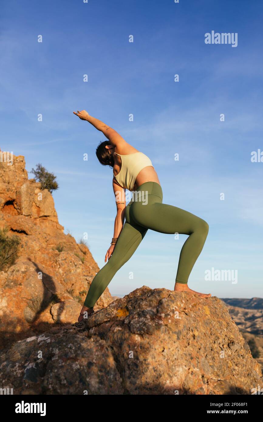Back view of unrecognizable flexible female standing with raised arm ...