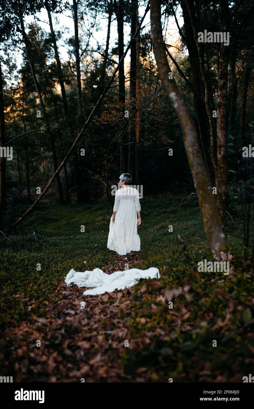 Full body of anonymous female wearing white dress standing near green ...