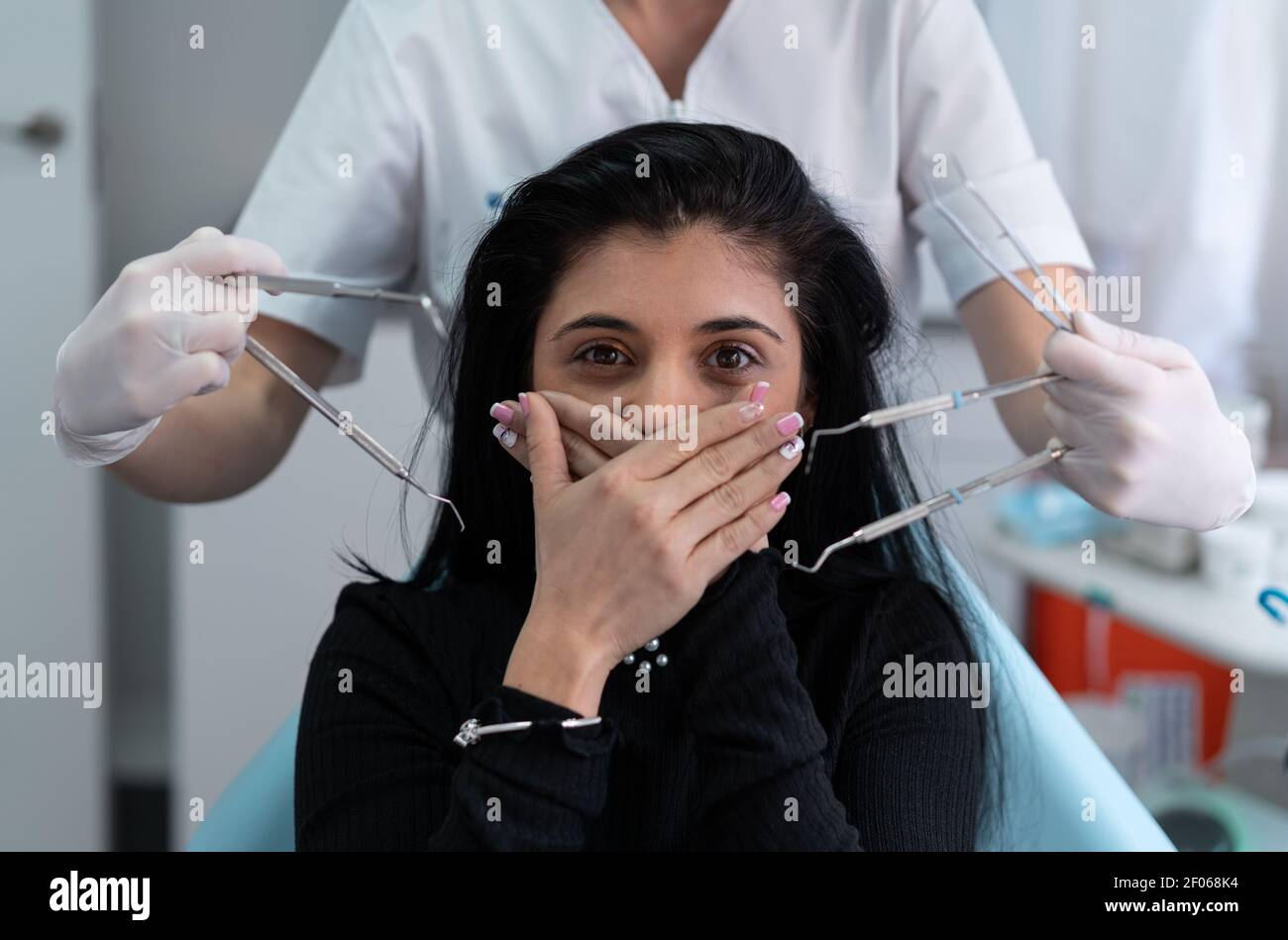Young frightened female patient looking at camera and covering mouth ...