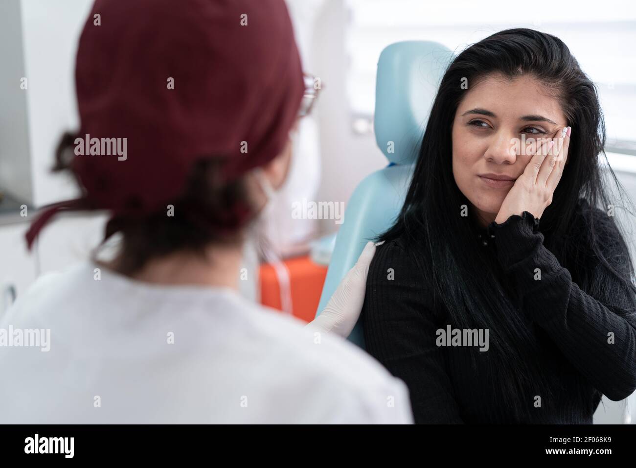 Back view of unrecognizable doctor and displeased female patient in ...