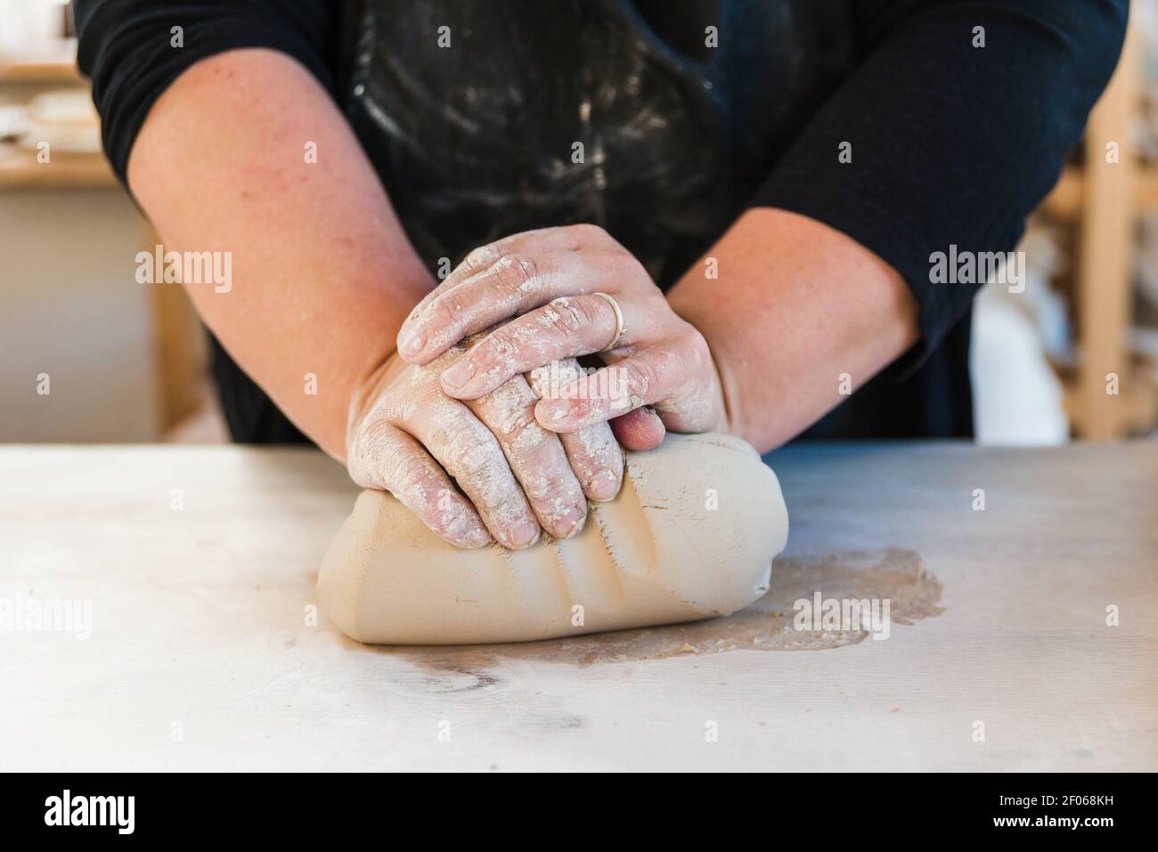 Crop unrecognizable female master in black casual outfit rolling clay ...