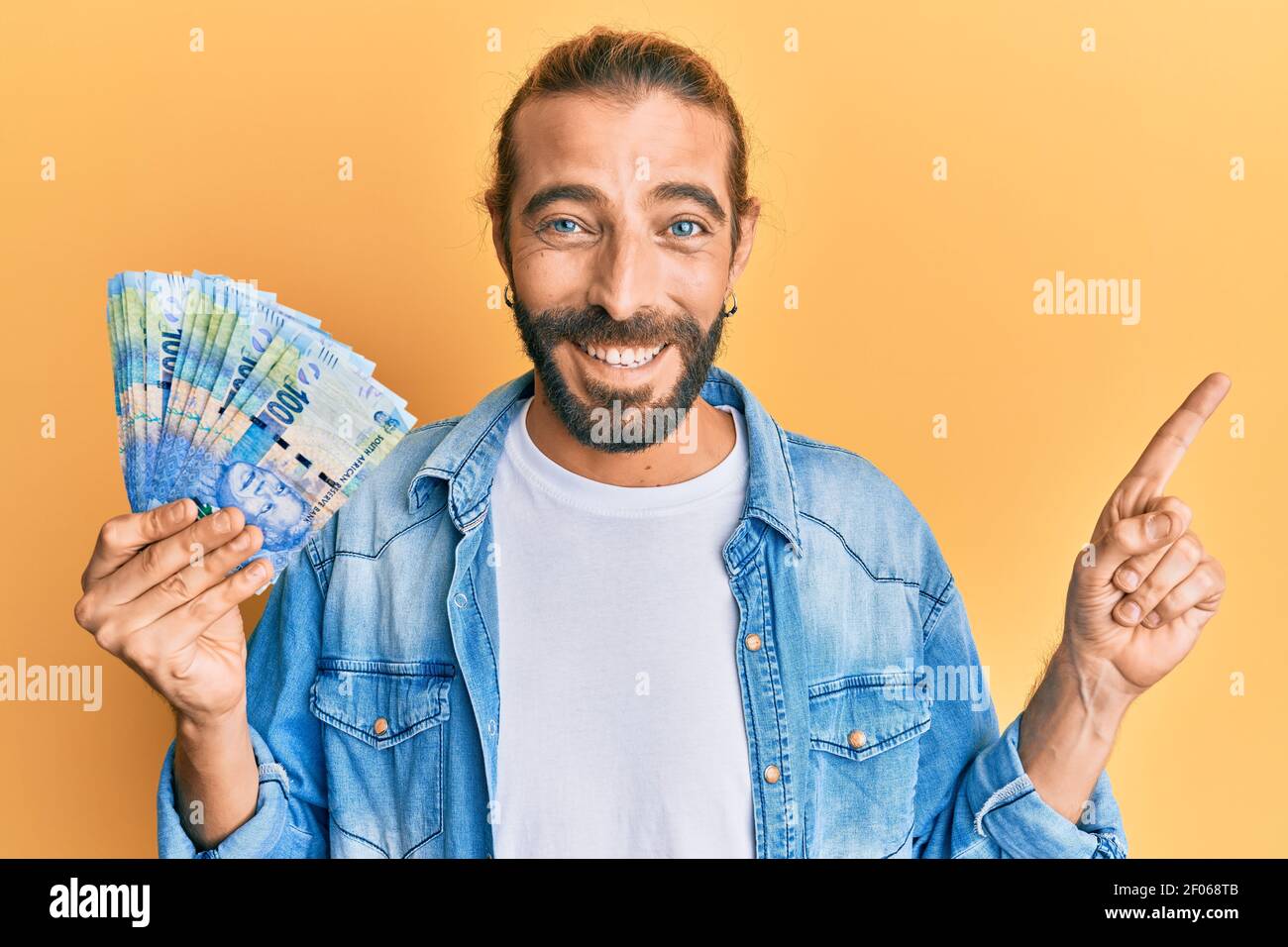 Attractive man with long hair and beard holding south african 100 rand ...