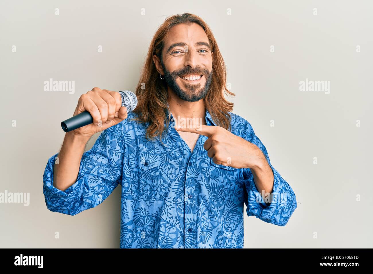 Attractive man with long hair and beard singing song using microphone ...