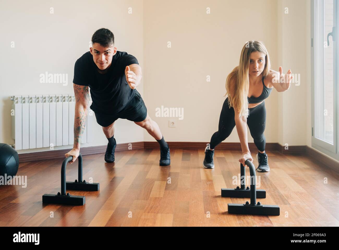 Determined man and Woman practicing exercise using steel push ups ...