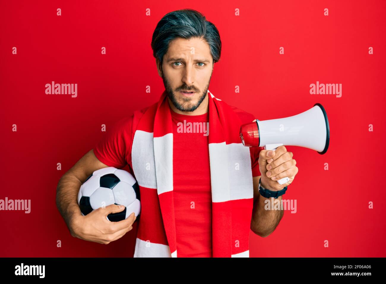 Young hispanic man football hooligan holding ball using megaphone ...