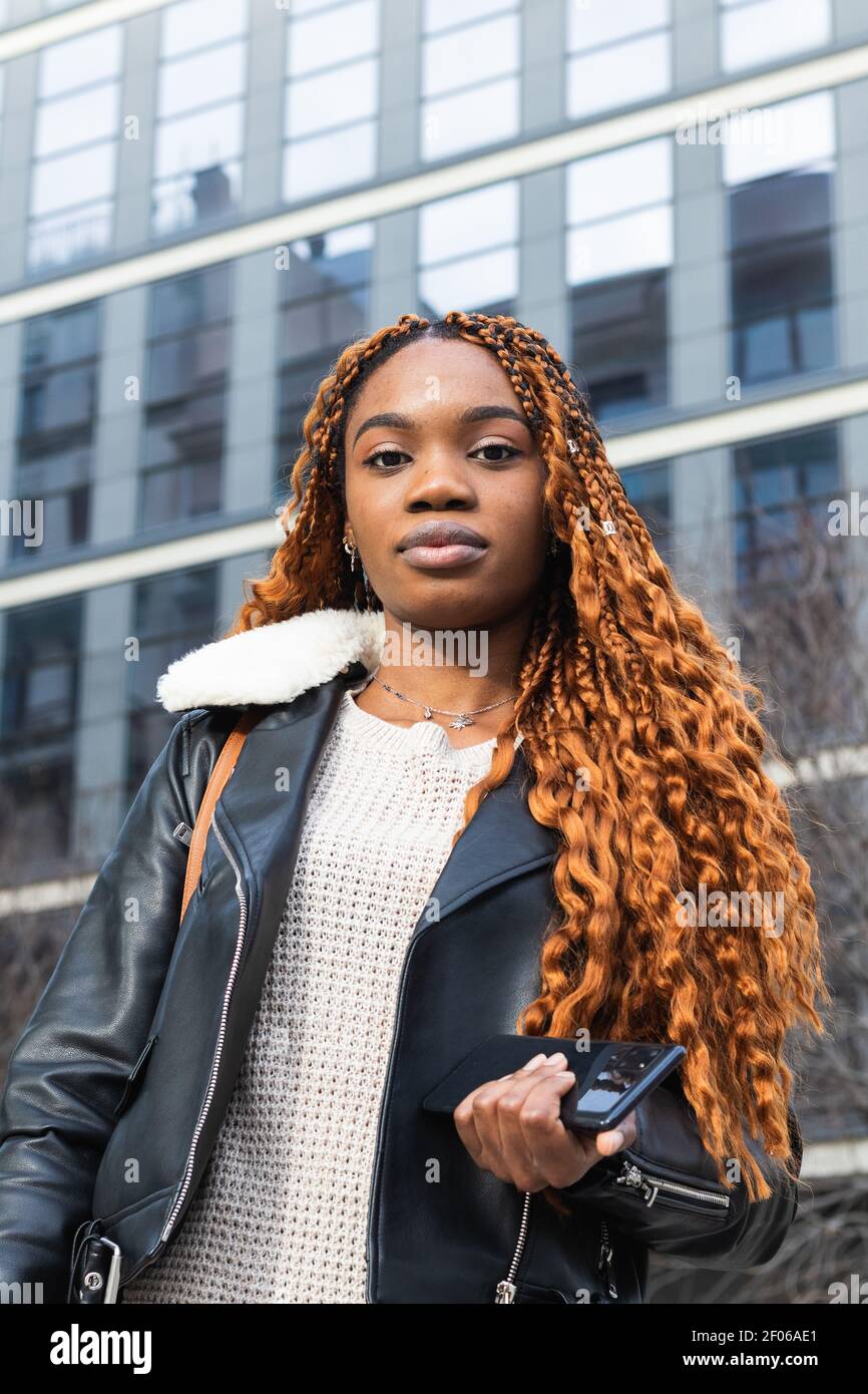 Side view of dreamy young black female with textbook and Afro braids ...