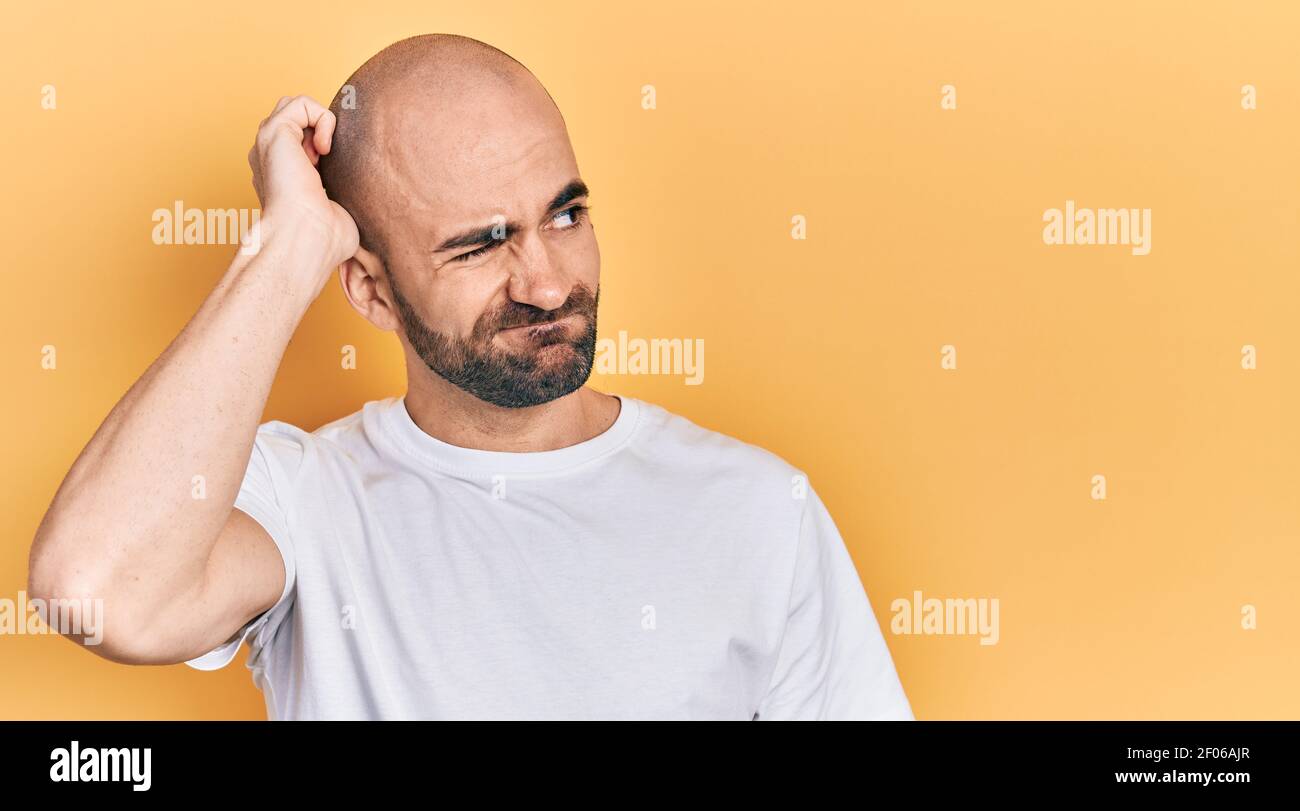 Young bald man wearing casual white t shirt confuse and wondering about ...