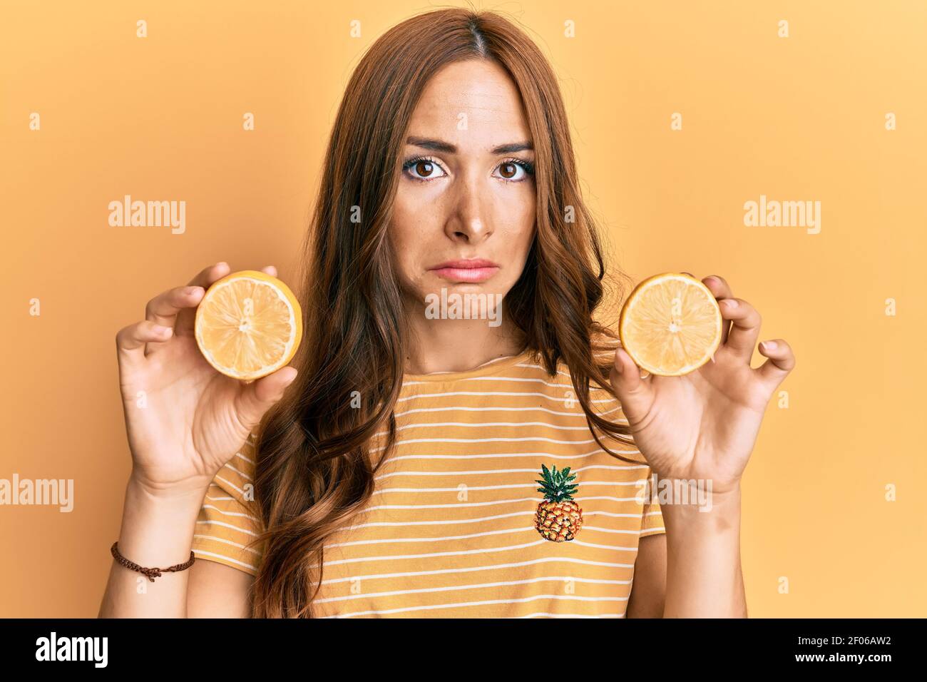 Young brunette woman holding fresh orange depressed and worry for ...