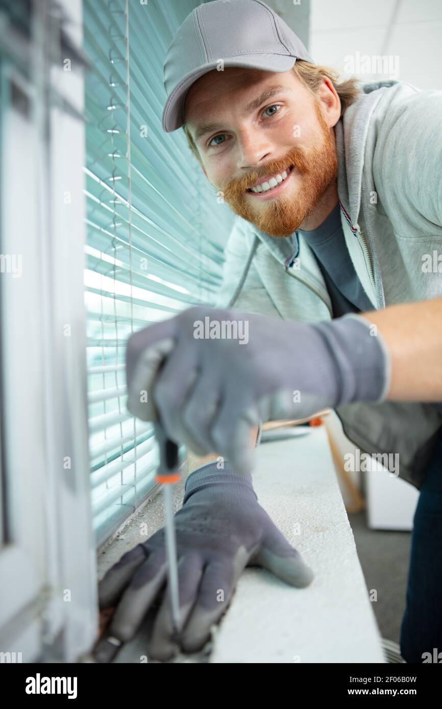 service man installing window with screwdriver Stock Photo - Alamy