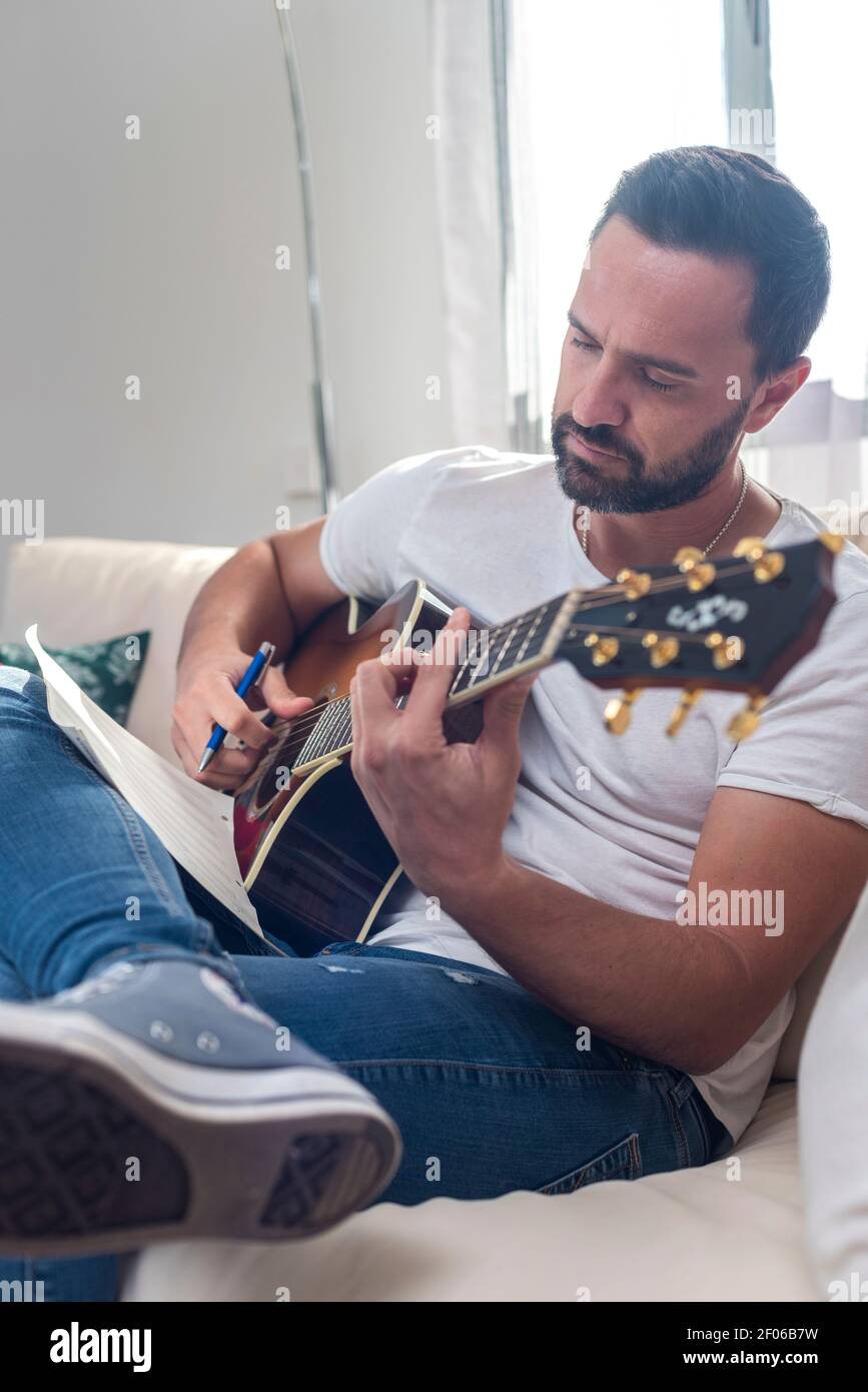 Concentrated young bearded ethnic male musician in casual clothes ...