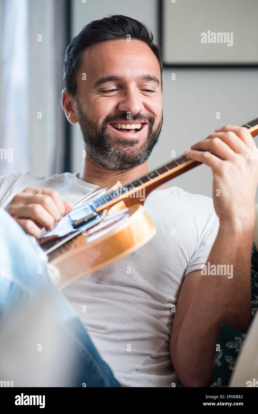 Happy adult ethnic male musician in casual clothes relaxing on ...