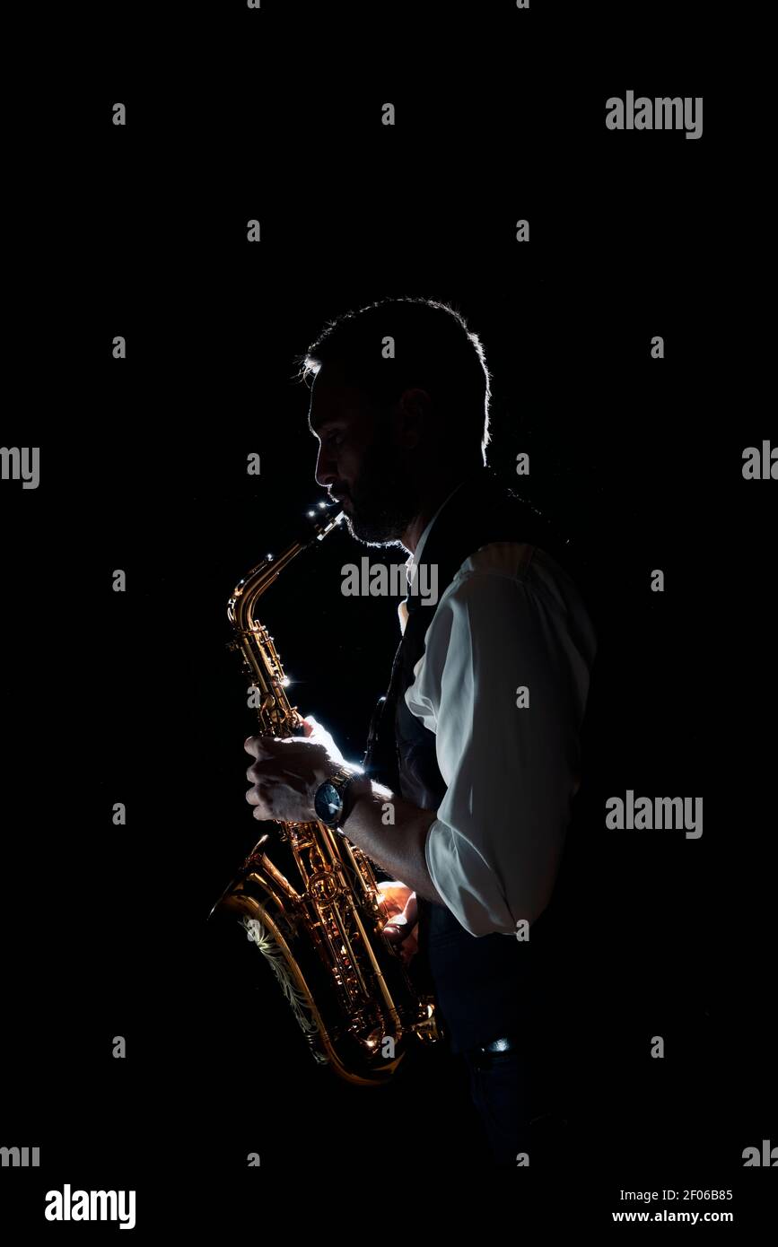 Side view of male musician in classy outfit playing alto saxophone ...