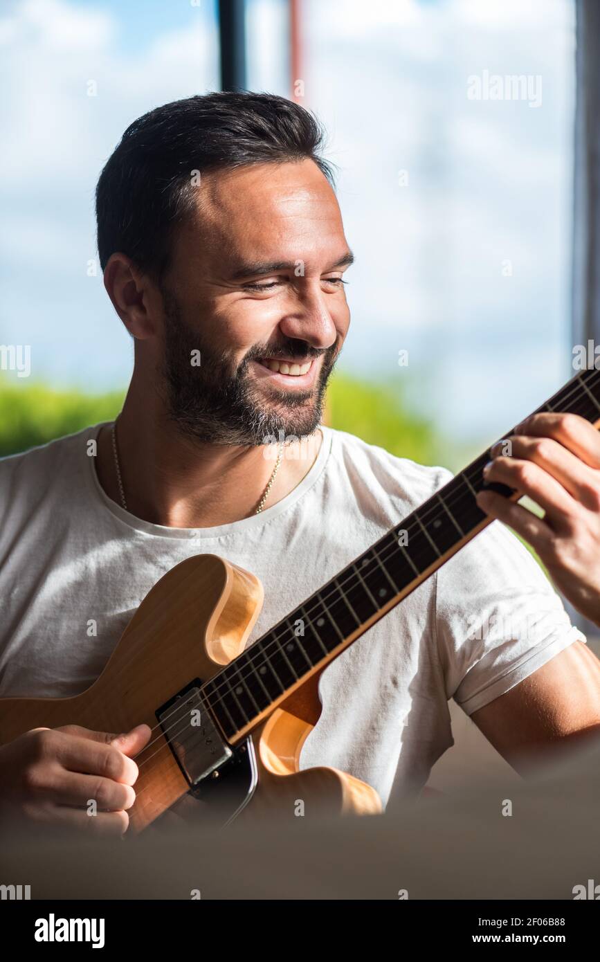 Happy adult ethnic male musician in casual clothes relaxing on ...