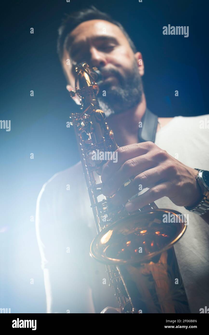 Male musician in classy outfit playing alto saxophone during jazz ...