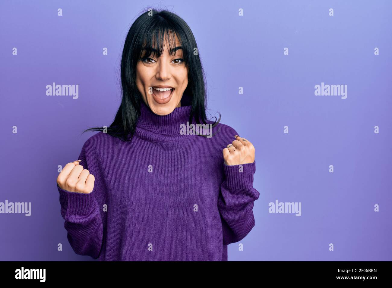Young brunette woman with bangs wearing turtleneck sweater celebrating ...