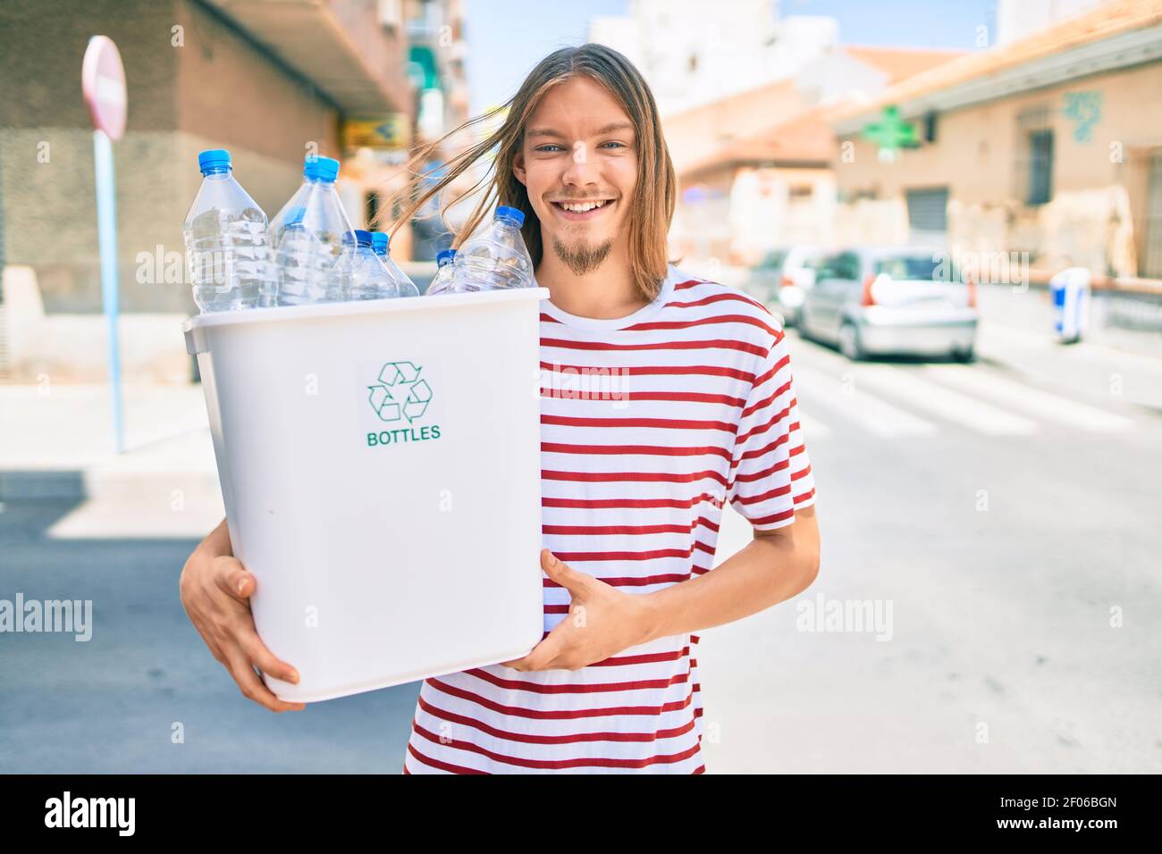 Young caucasian man with blond long hair and beard recycling plastic ...