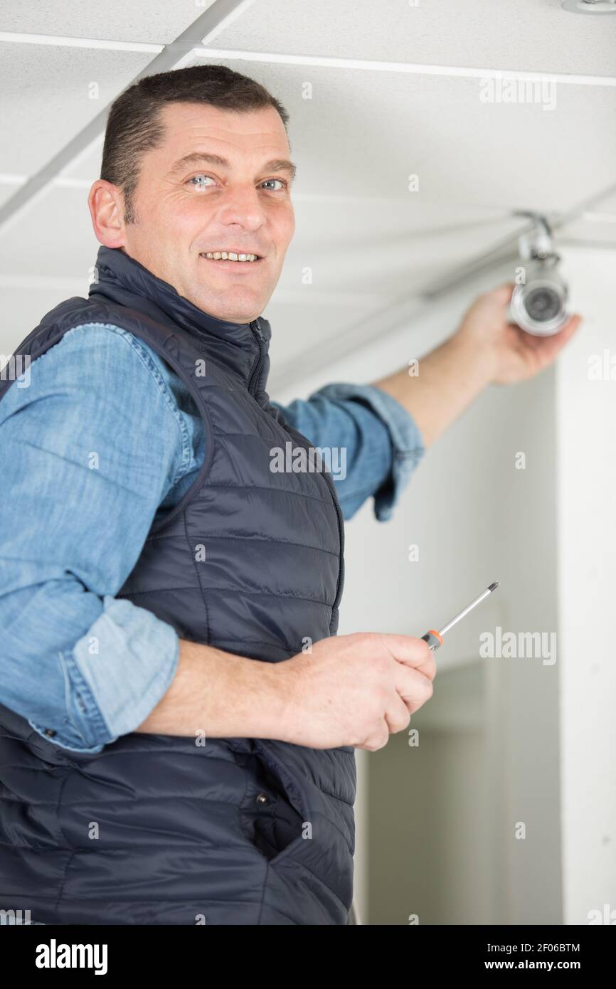 man mounting a security camera to the ceiling Stock Photo - Alamy