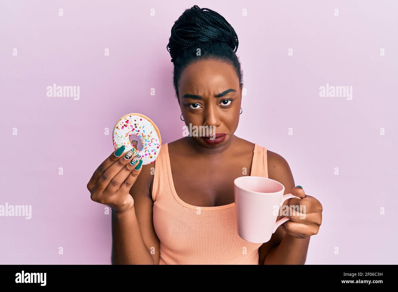 Young african american woman eating doughnut and drinking coffee ...
