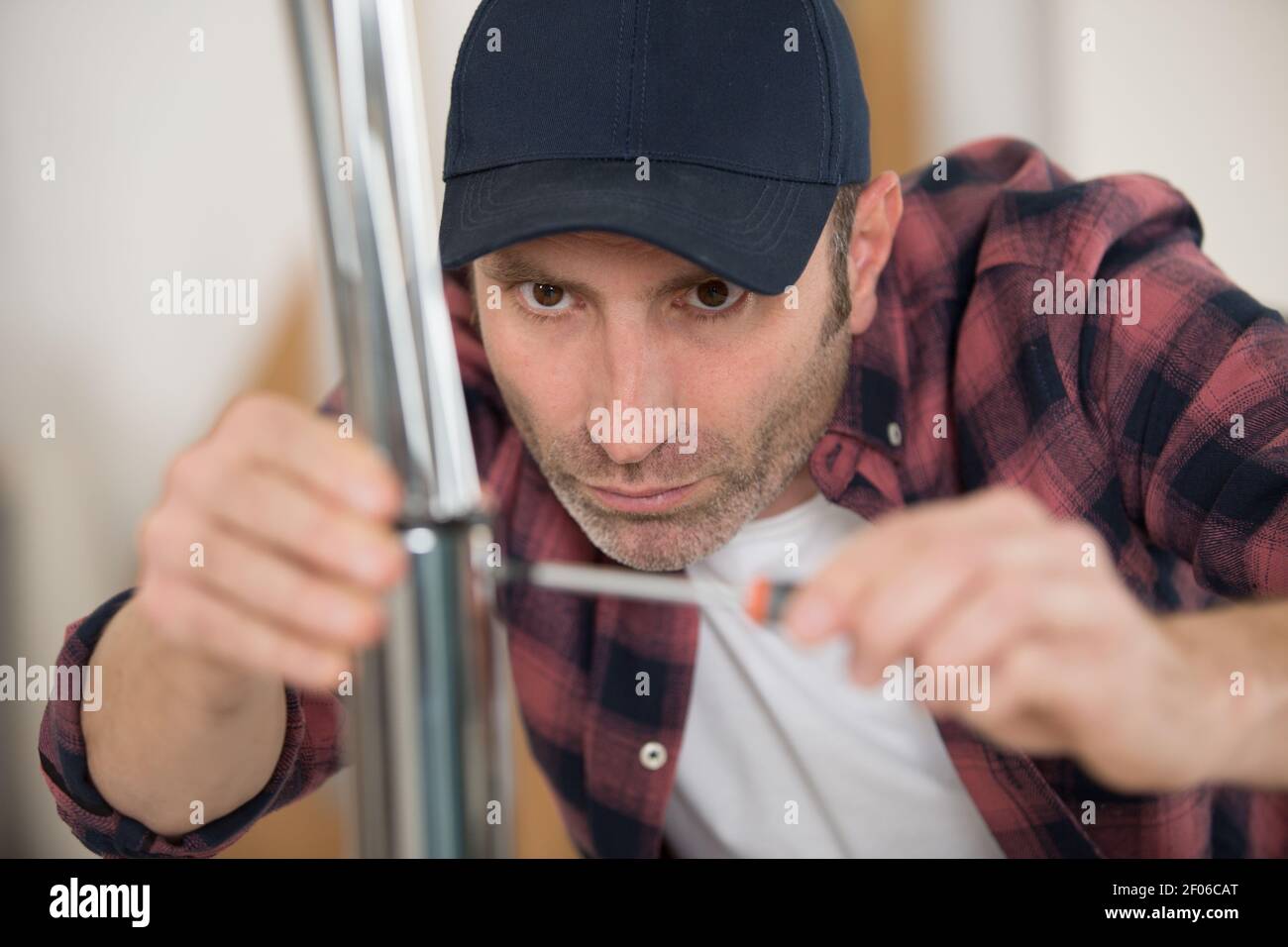 male handyman in uniform fixing table leg with screwdriver Stock Photo ...