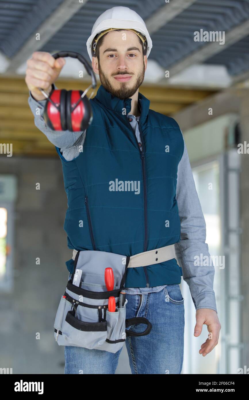 young attractive builder holding ear protection Stock Photo - Alamy