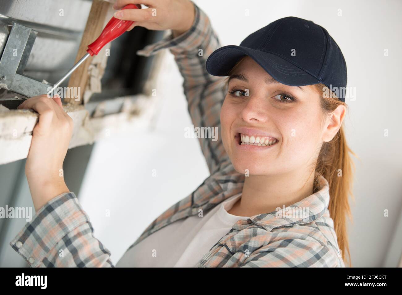 smiling female worker installing a window shutter Stock Photo - Alamy