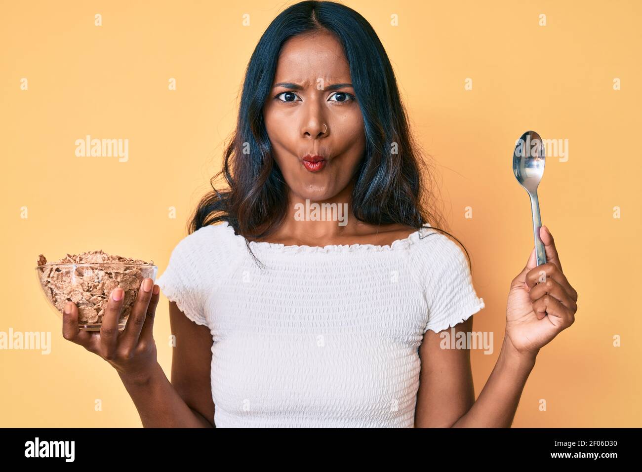 Young indian girl eating healthy whole grain celears making fish face ...