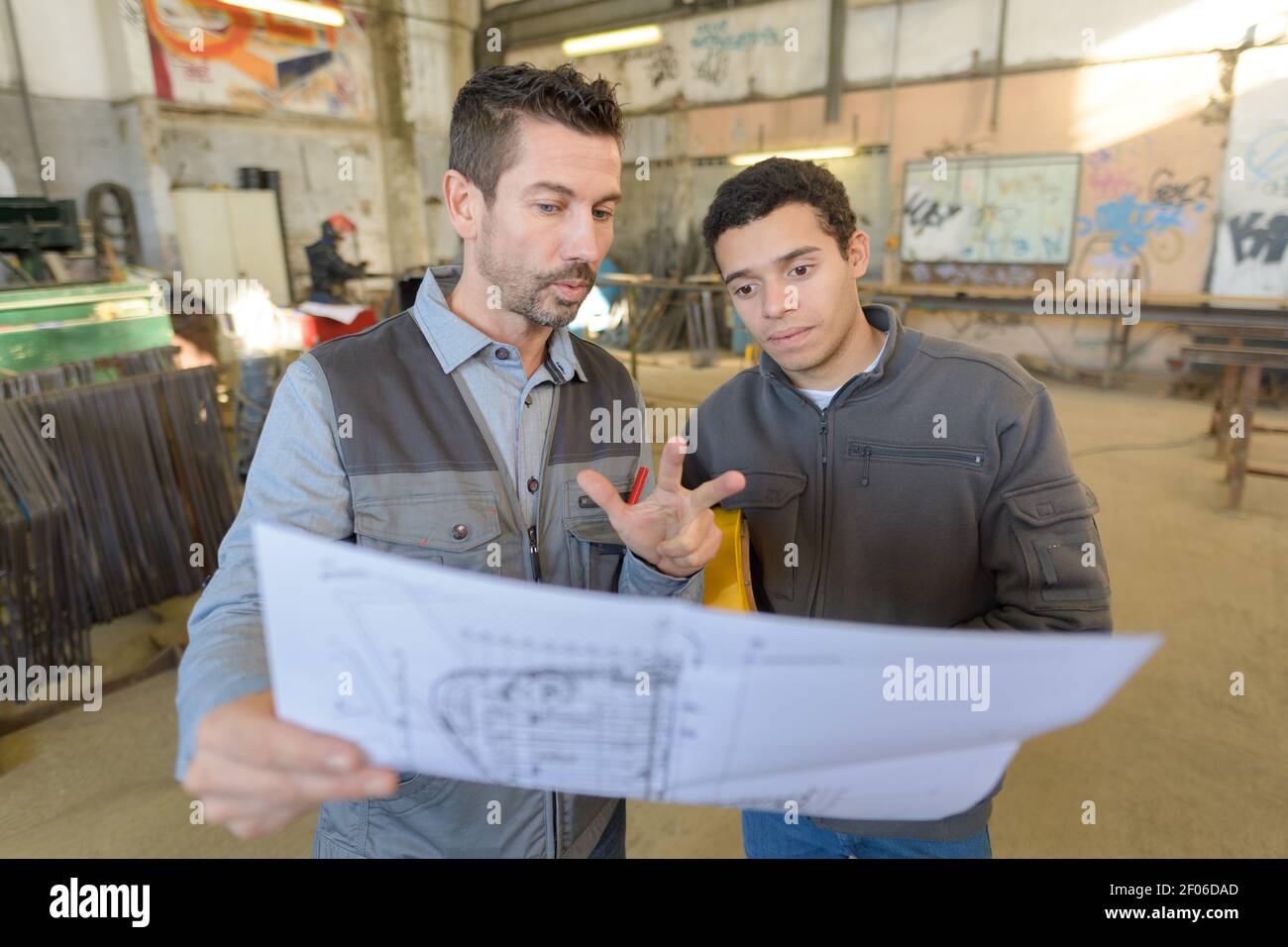 engineer explaining his blueprint to the factory staff Stock Photo - Alamy
