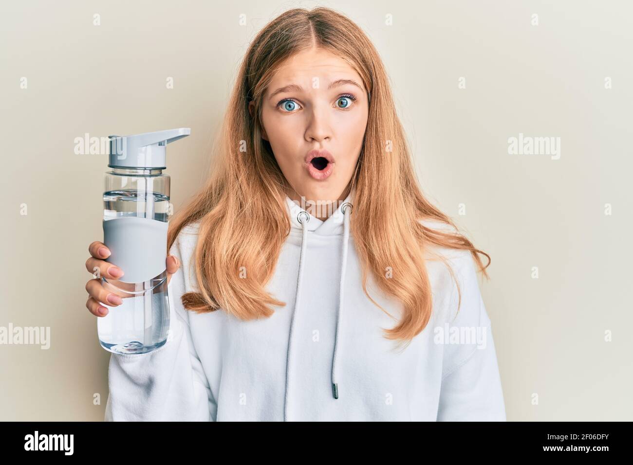 Beautiful young caucasian girl wearing sportswear drinking bottle of ...