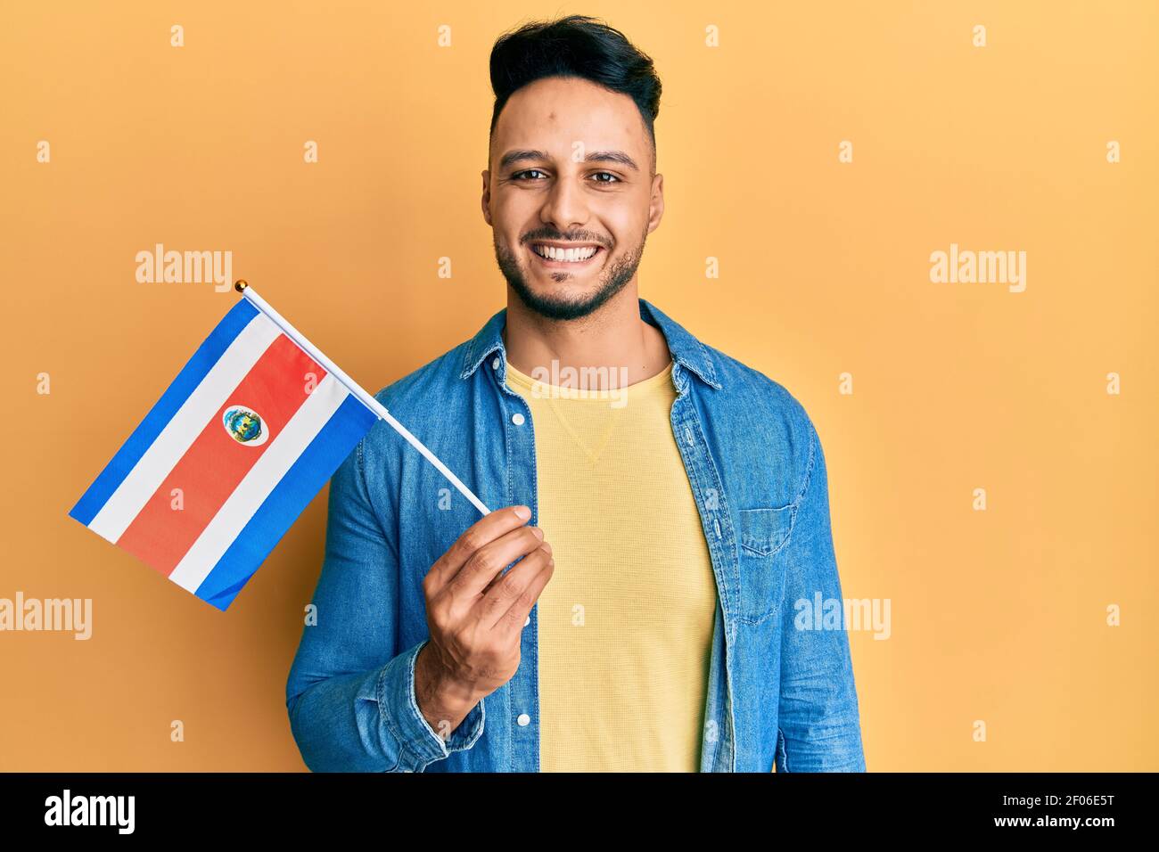 Young arab man holding costa rica flag looking positive and happy ...
