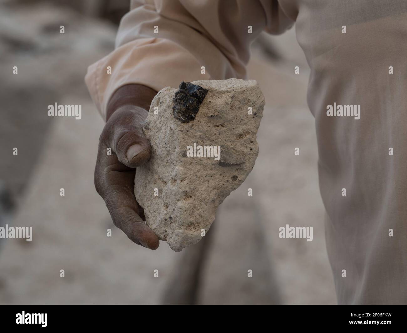 Quarry worker holding white sillar rhyolite volcanic rock stone brick ...