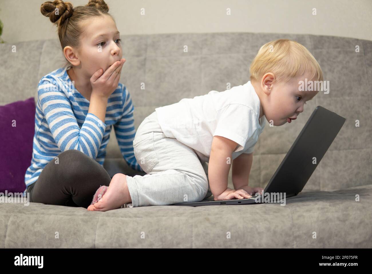 Little boy watching laptop while his sister wonder Stock Photo - Alamy