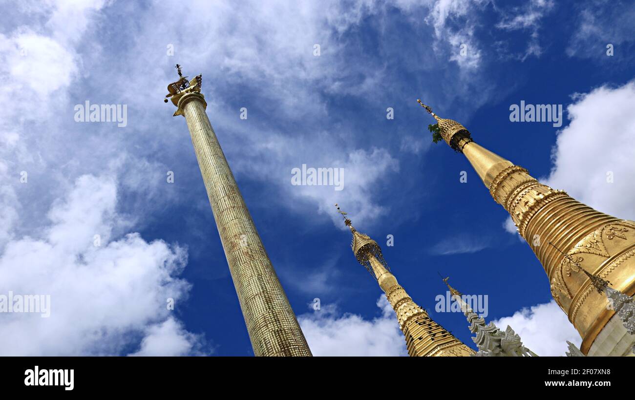 A tilted shot of a tall prayer pillar and pagodas pointed towards a ...