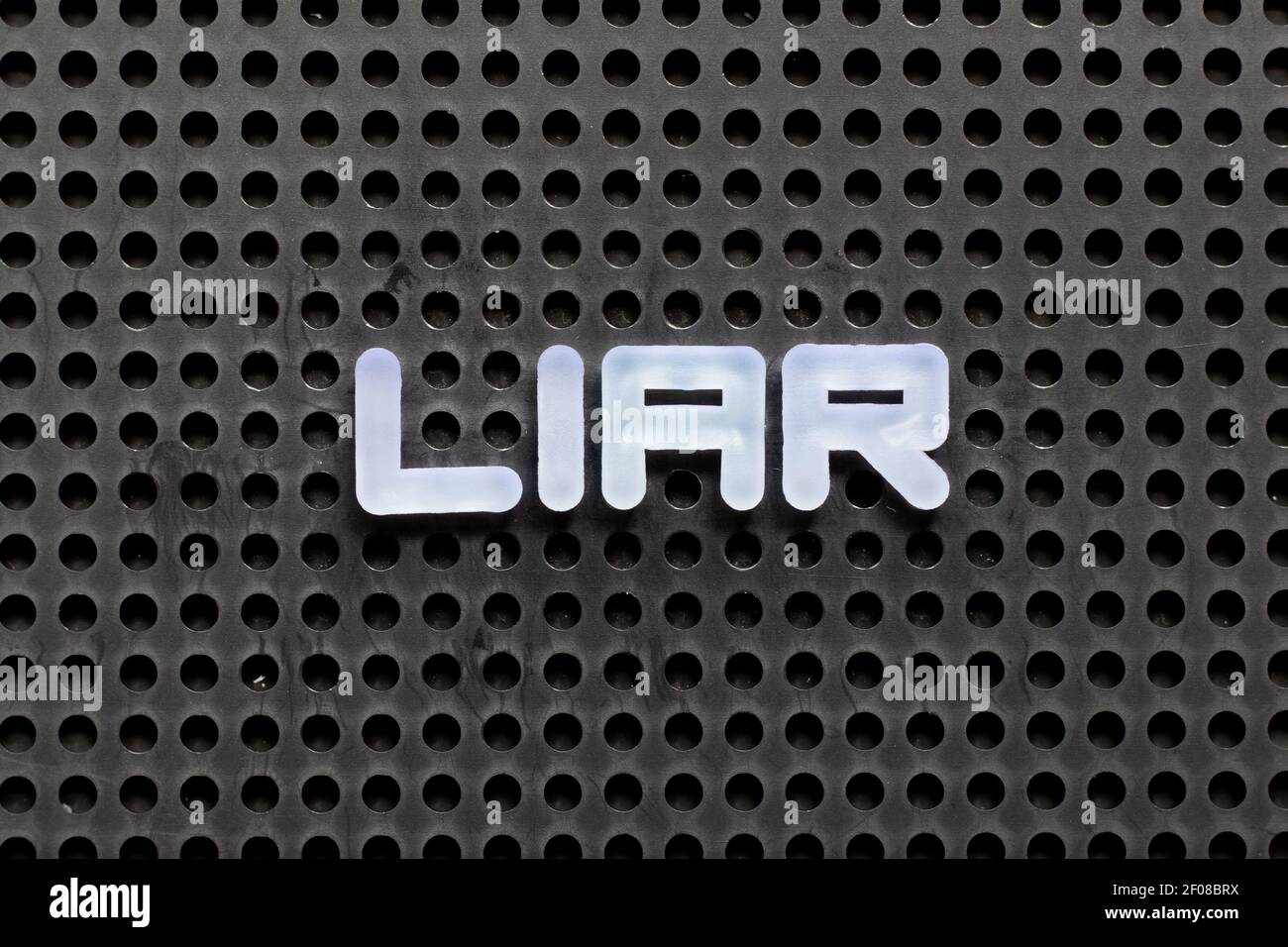 White color letter in word liar on black pegboard background Stock ...
