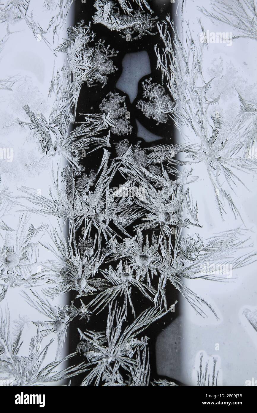 Ice crystals growing on a window pane in the middle of winter, in ...