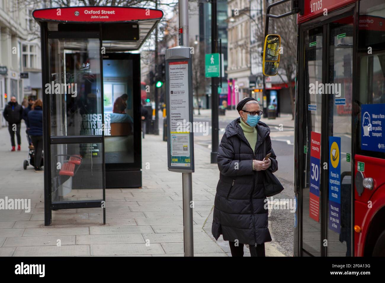 A lady wearing a face mask boards a bus in Oxford Street. (Photo by ...